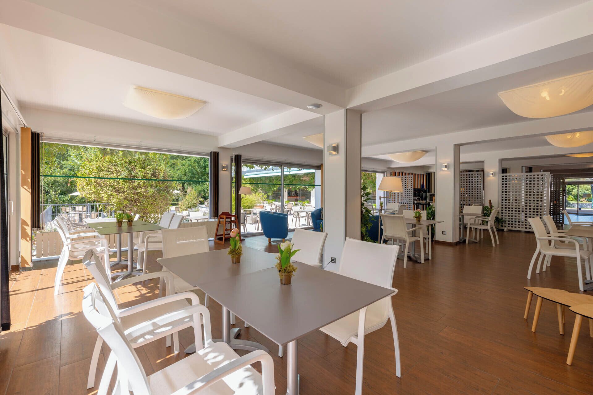 Amplo espaço interno com uma mesa comprida e cadeiras, área de cozinha e vista para o exterior.