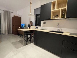Uma cozinha moderna com uma ilha central, armários pretos e bancada de madeira.