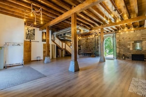 Um quarto amplo com vigas de madeira, paredes de pedra e lareira.
