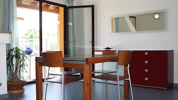 Uma área de refeições com mesa e cadeiras de madeira, um armário vermelho e uma planta em vaso.