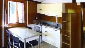 Uma cozinha compacta com uma mesa de jantar, cadeiras, geladeira e forno embutido.