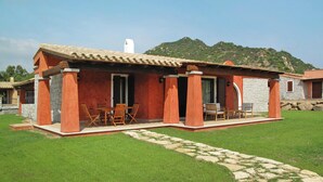 Uma casa com um pátio, pilares de pedra e vista para uma montanha.
