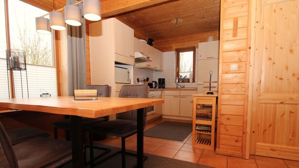 Uma cabana de madeira aconchegante com sala de jantar, cozinha e um pequeno espaço de estar.