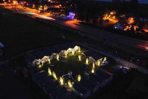 Vista aérea de um bairro residencial à noite, com casas e uma estrada.