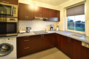 Cozinha moderna com eletrodomésticos de aço inoxidável, armários de madeira e uma janela grande.