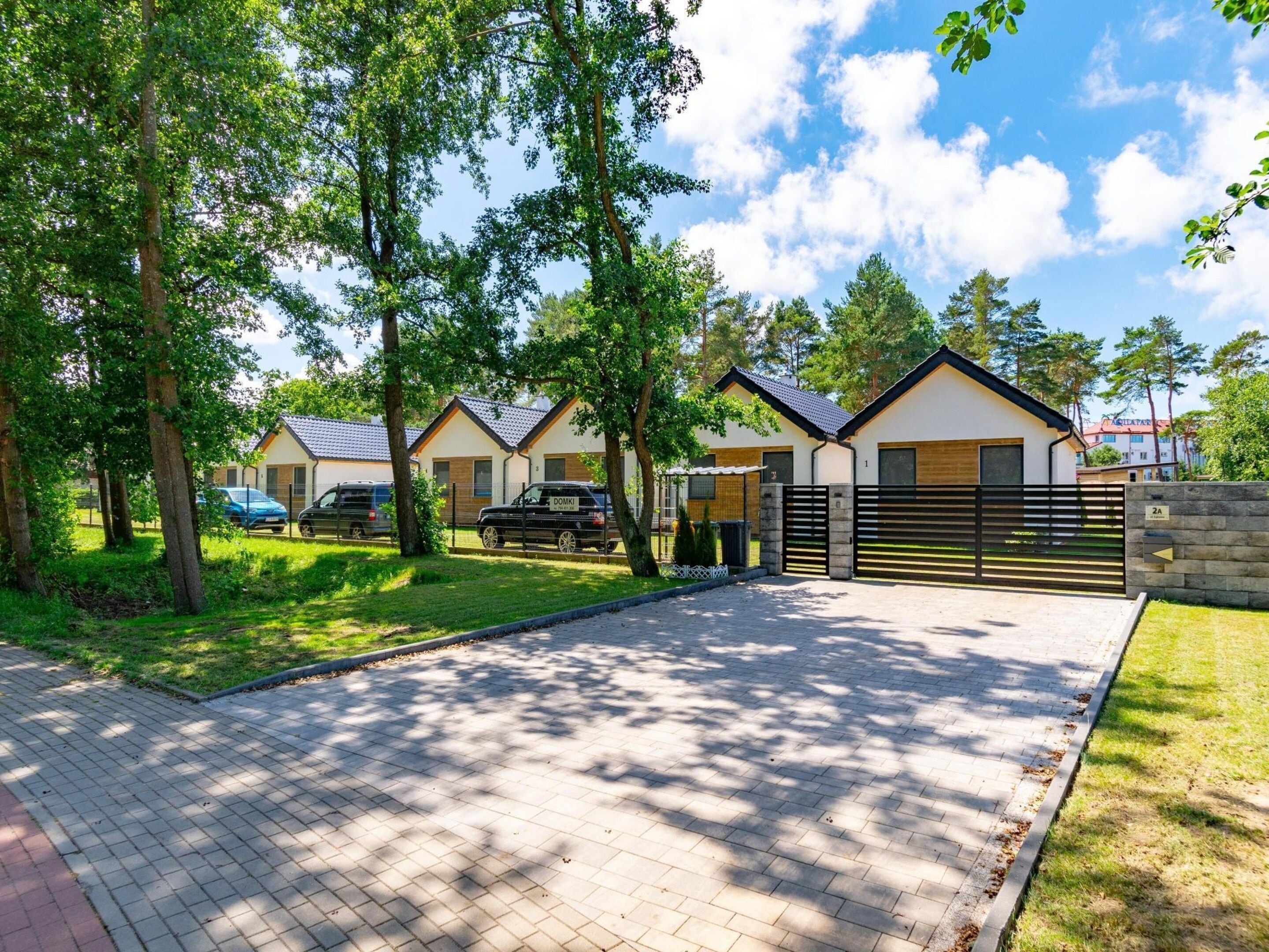 Zona residencial com casas modernas, calçada pavimentada e portão fechado.