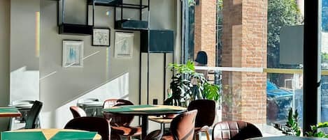 Interior moderno de café, com mesas, cadeiras e escada com corrimão preto.