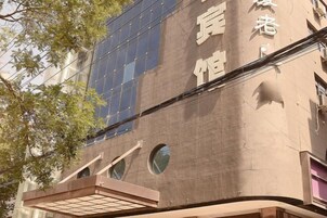 Um edifício com fachada bege, janelas amplas e instalação visível de painéis solares.
