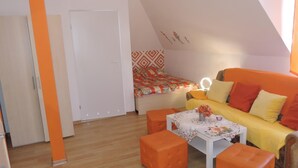 Quarto com cama beliche, sofá laranja e pufes.