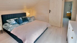 Quarto com cama, mesa de cabeceira, abajur e guarda-roupa.