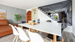 Uma sala de jantar moderna com uma mesa branca, cadeiras pretas e um armário de madeira.