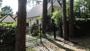 Uma casa rodeada por árvores altas com uma cerca de metal à frente.