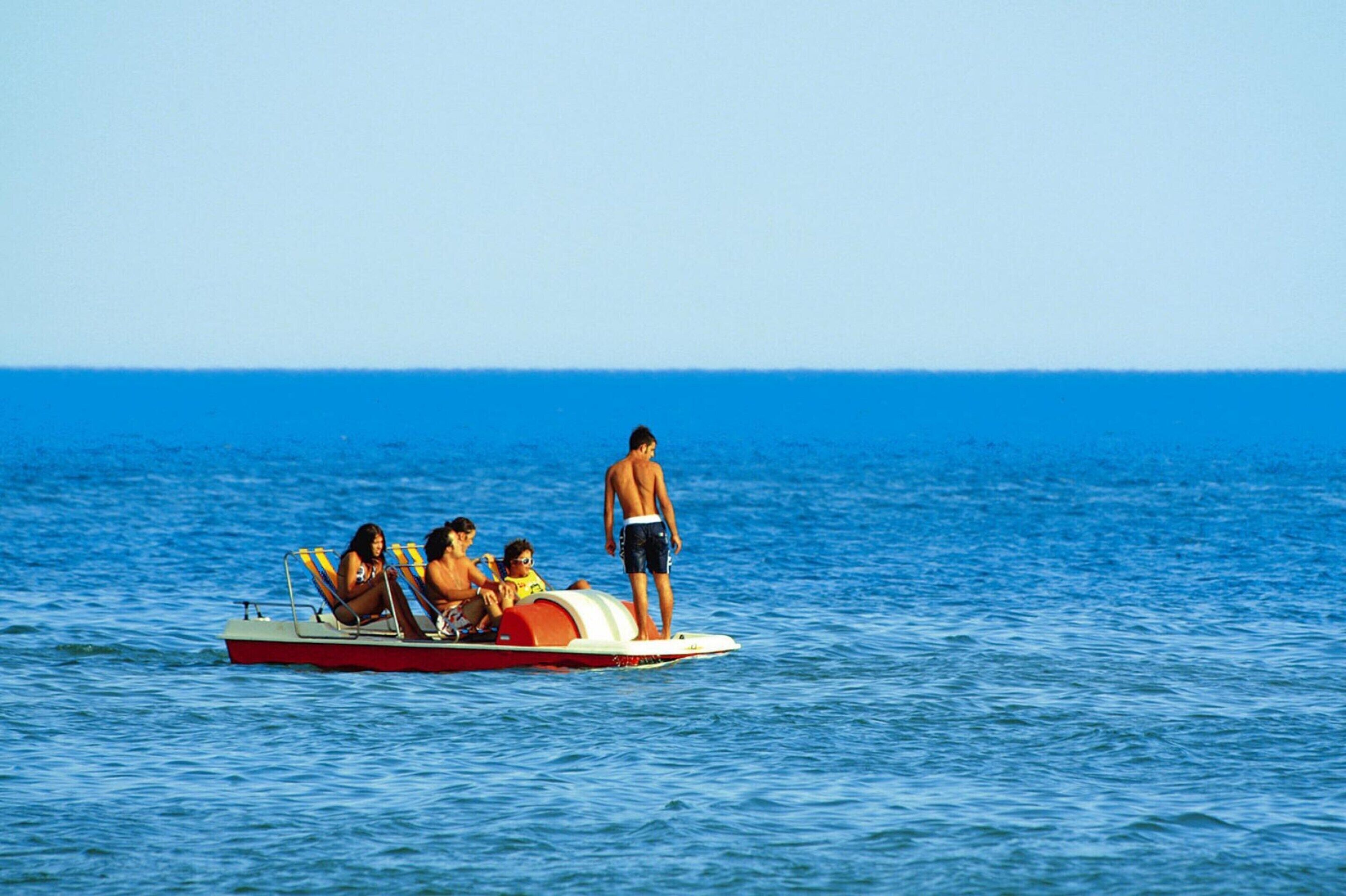 Um barco pequeno com pessoas flutuando na água.