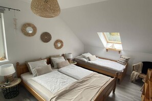 Quarto com duas camas, janela e luminária suspensa.