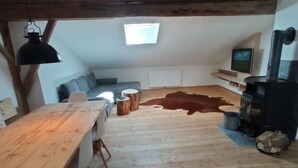 Um interior rústico com uma mesa de jantar de madeira, um sofá, uma TV e uma lareira a lenha.