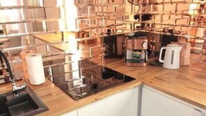Cozinha moderna com bancada de madeira, eletrodomésticos de aço inoxidável e forno embutido.