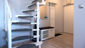 Escada moderna com um arranhador para gatos integrado, um pequeno espaço de estar e uma porta que dá para outro quarto.