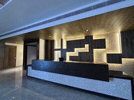Balcão de recepção com design moderno, destacando um tampo escuro e padrões geométricos iluminados na parede ao fundo.