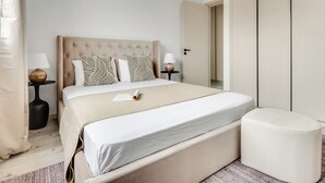 Quarto bem organizado com uma cama grande, luminárias de cabeceira, mesa de cabeceira, luz para leitura e um guarda-roupa.