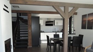 Um interior moderno com área de jantar, cozinha e escadaria.