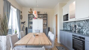 Cozinha moderna com armários cinza, uma mesa de jantar de madeira e um revestimento de azulejos.