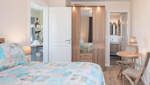 Quarto com uma cama, uma escrivaninha, uma cadeira e um banheiro visível por uma porta aberta.