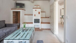 Uma sala de estar com sofá, mesa de centro de vidro, lareira e televisão na parede.