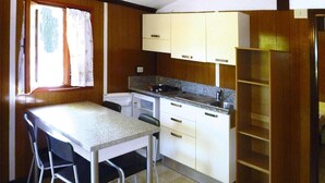 Uma cozinha compacta com uma mesa de jantar, cadeiras, geladeira e forno embutido.