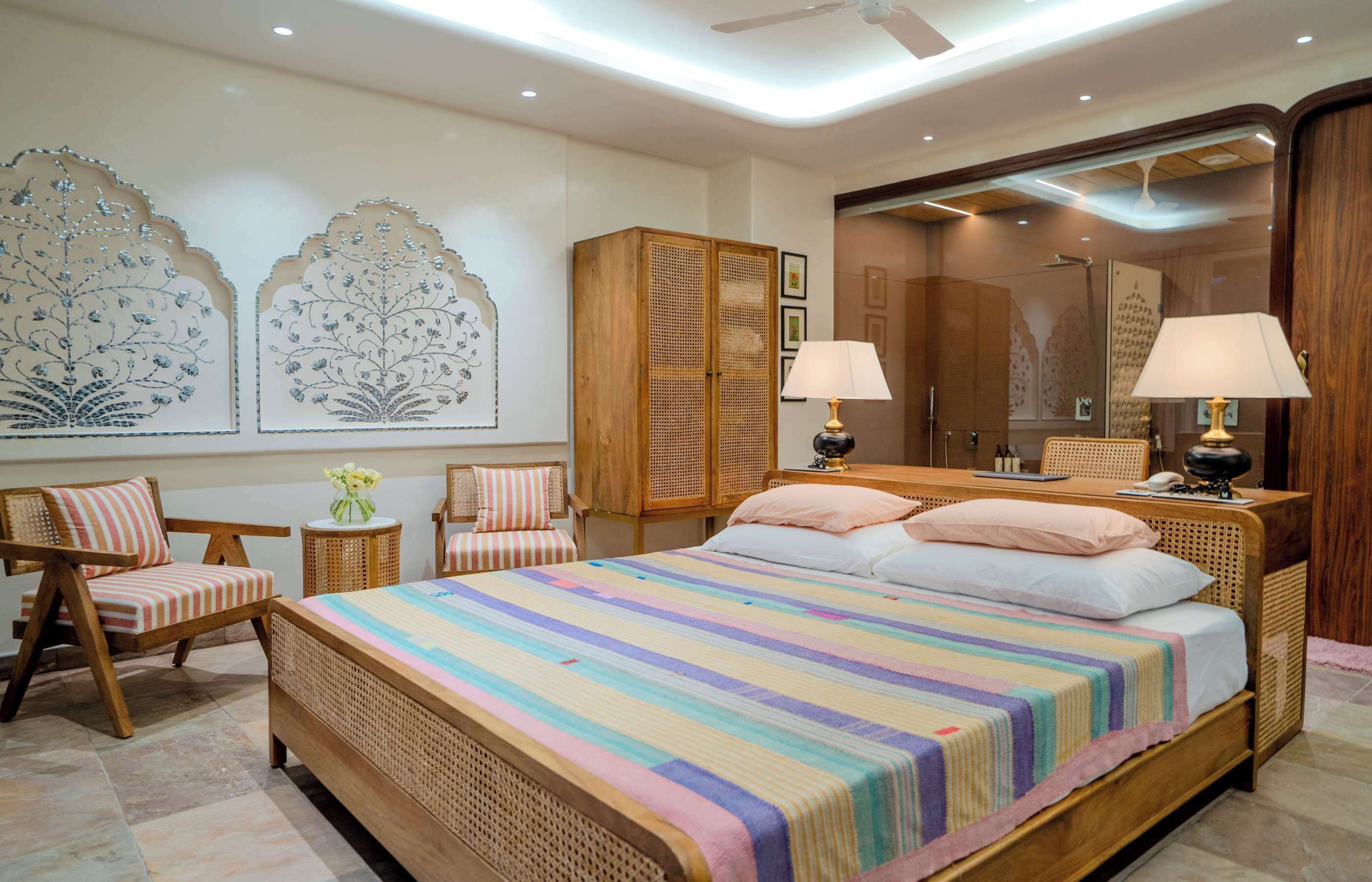 Um quarto espaçoso com uma cama grande, duas mesas de cabeceira com luminárias, um guarda-roupa de madeira e arte decorativa na parede.