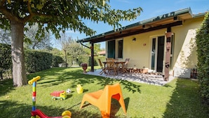 Uma casa com um pátio, área de jantar e uma árvore no quintal.