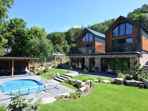 Uma casa moderna de dois andares com piscina, área de estar externa e um jardim bem cuidado.
