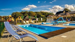 Piscina com espreguiçadeiras, toboágua e uma pequena cascata.