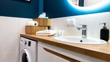 Uma casa de banho moderna com máquina de lavar roupa, lavatório e artigos de higiene pessoal.