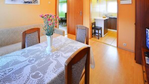 Uma sala de jantar com uma mesa posta para dois, um vaso com flores e um quadro na parede.