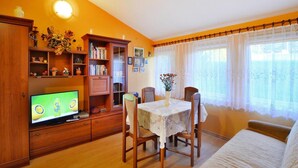 Uma sala de estar acolhedora com um armário de madeira, uma televisão e uma mesa de jantar com cadeiras.