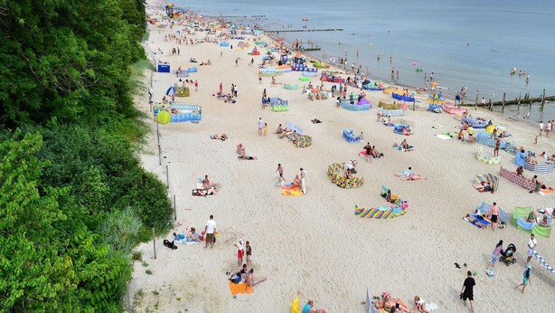 Uma praia com vários guarda-sóis e cadeiras de praia, indicando um destino turístico popular.