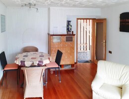 Uma sala de jantar com uma mesa redonda, quatro cadeiras, um armário e um sofá.