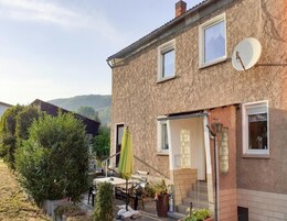 Uma casa de dois andares com um pátio, antena parabólica e um pequeno jardim.