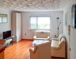 Uma sala de estar com sofá, televisão e janela com cortinas.