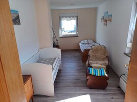 Quarto com berço, sofá, cadeira, janela e radiador.