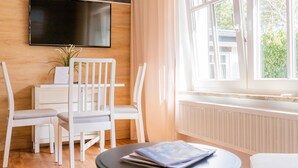 Uma sala de estar moderna com televisão de tela plana na parede, uma parede de destaque em madeira, uma janela grande com vista para vegetação e um radiador branco.