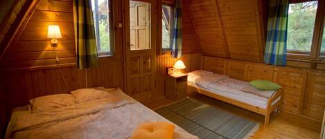 Um quarto de sótão acolhedor com duas camas, teto de madeira e vista para o exterior.