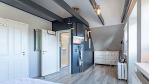 Quarto com uma cama, penteadeira, espelho e porta que dá para um banheiro.