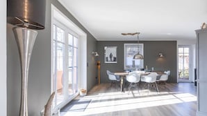 Uma cozinha ampla com área de refeições, grandes janelas e um lustre moderno.