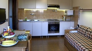 Cozinha compacta com fogão, forno, micro-ondas e área de jantar com uma fruteira.