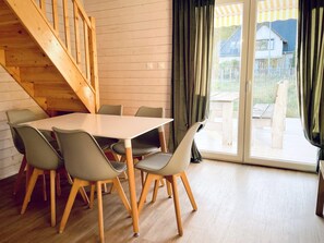 Quarto com escada de madeira, mesa com cadeiras e porta de vidro deslizante para área externa.