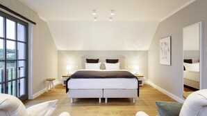Quarto moderno com uma cama grande, duas mesas de cabeceira, uma janela ampla e vista para o exterior.