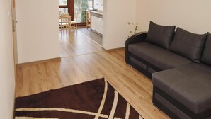 Uma sala de estar com um sofá cinza escuro, piso de madeira e tapete marrom.