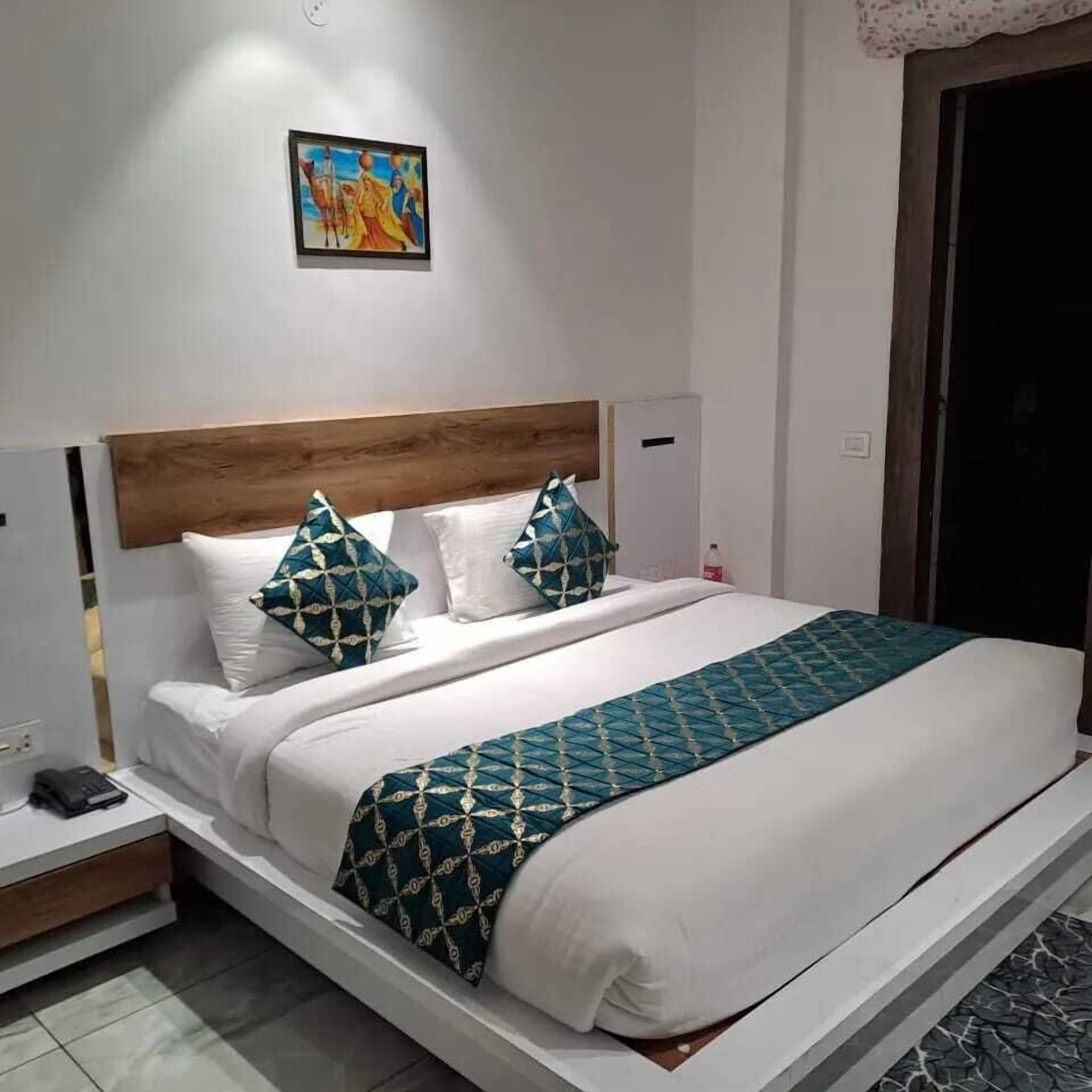 Uma cama bem arrumada com cabeceira de madeira, roupa de cama branca e almofadas estampadas.