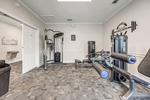Uma academia com diversos equipamentos de exercícios, uma placa na parede e um carpete estampado.